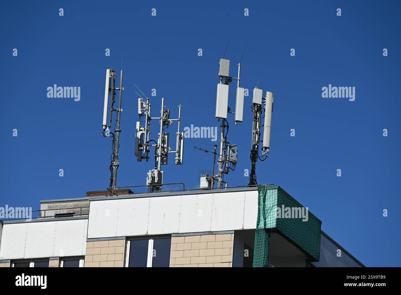 Mobilfunkmast, Richtfunkmast auf einem Hausdach vor blauem Himmel Antennenmast.Ausbau,Mobilfunk ...