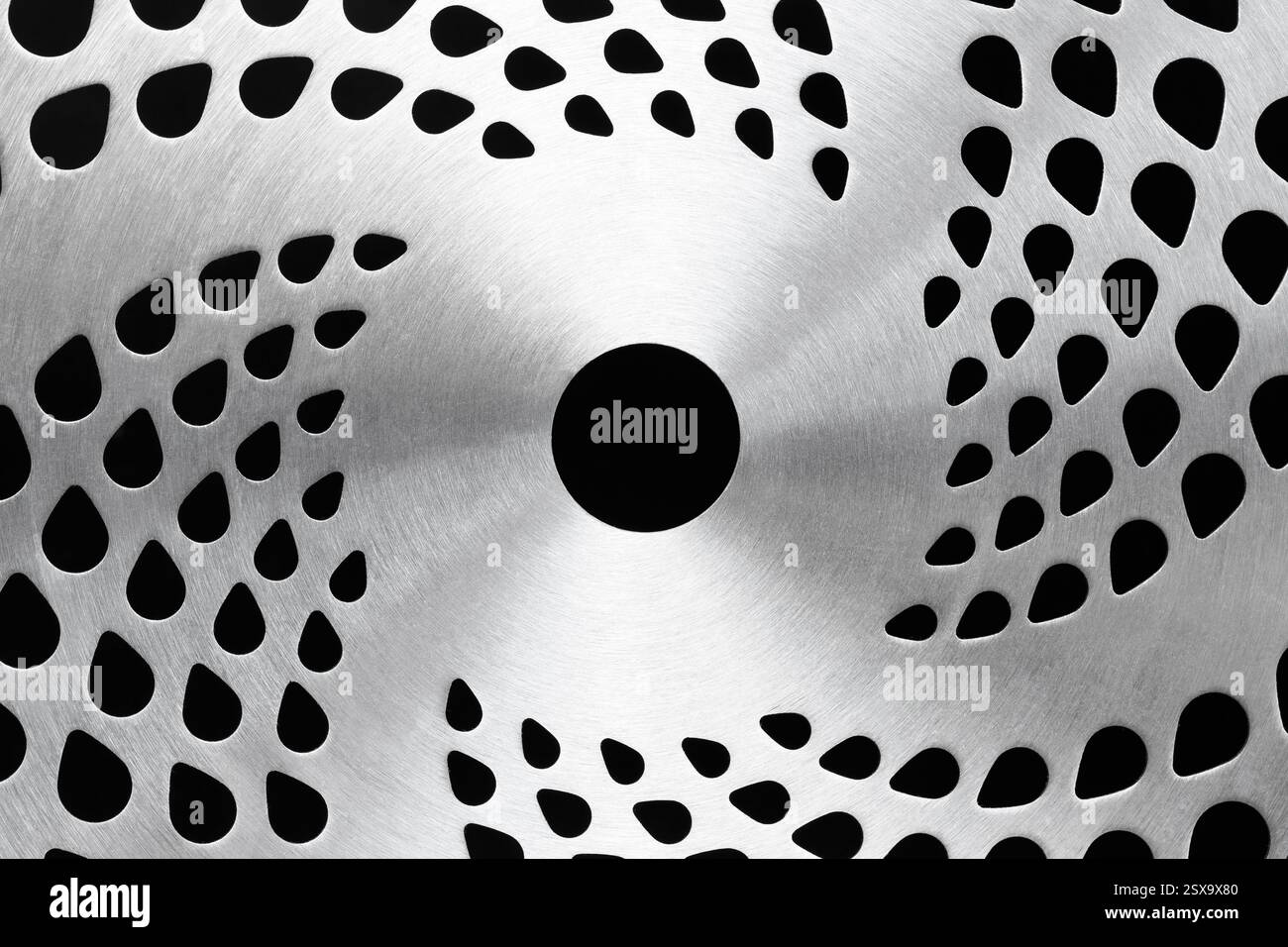 Metal disk with holes arranged in a spiral. Abstract technological ...