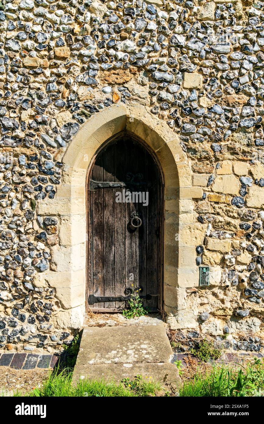 Wooden door in the flint stone wall of the 12th century church of St ...