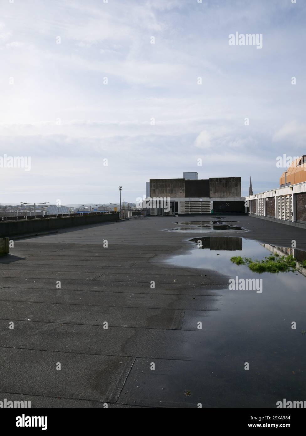 Water pooled in a puddle on one side of a large flat roof over a ...