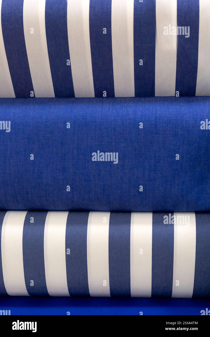 Colourful bolts of blue and white fabric cloth on a market stall for ...