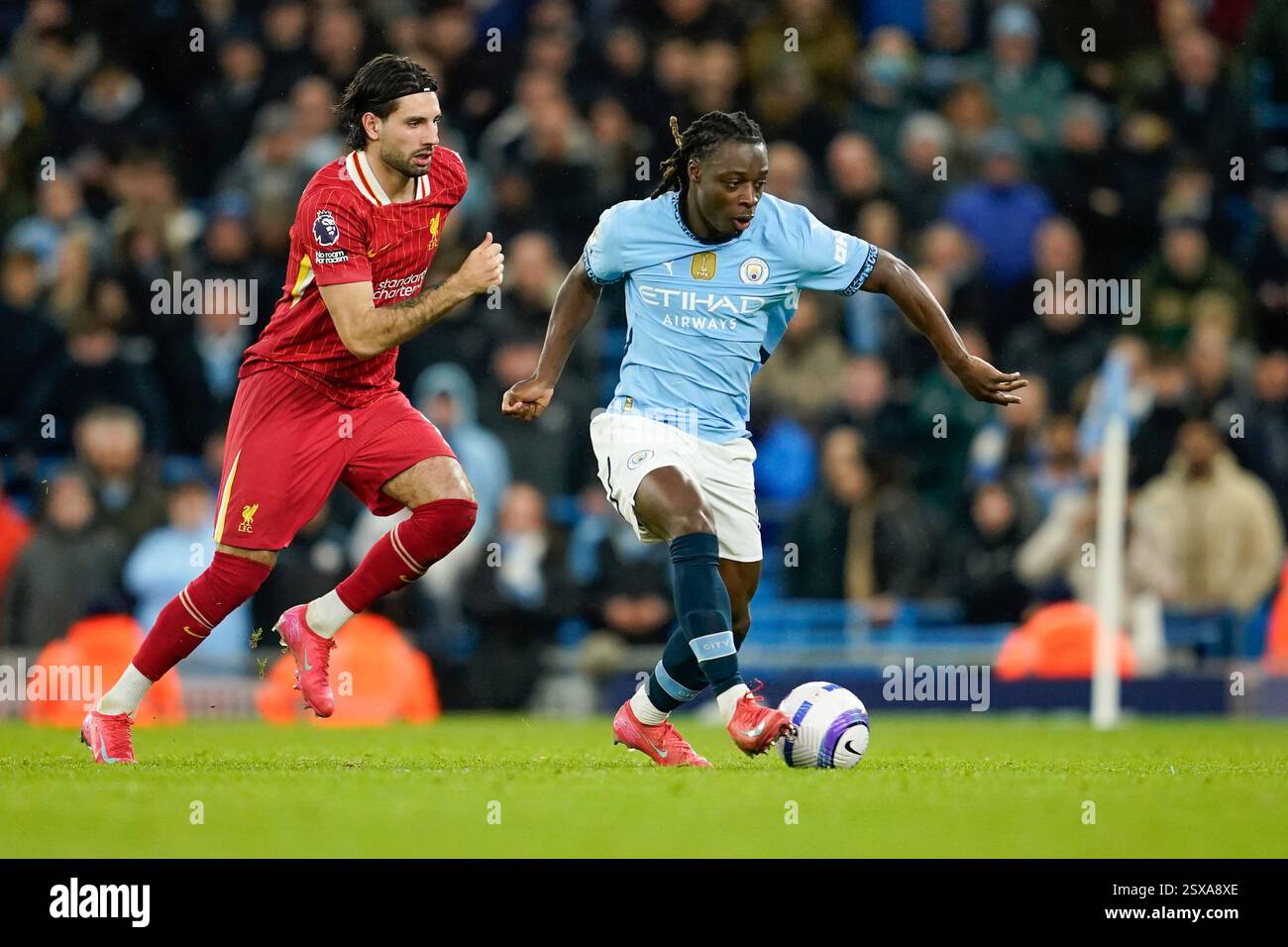 Manchester City's Jeremy Doku, right, dribbles the ball followed by ...