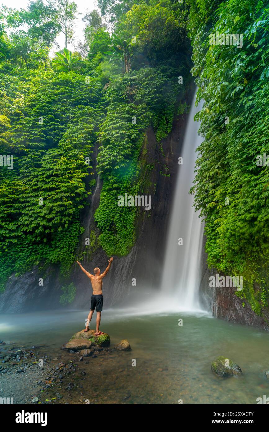 View of man embracing the power of Melanting waterfall, Kabupaten ...