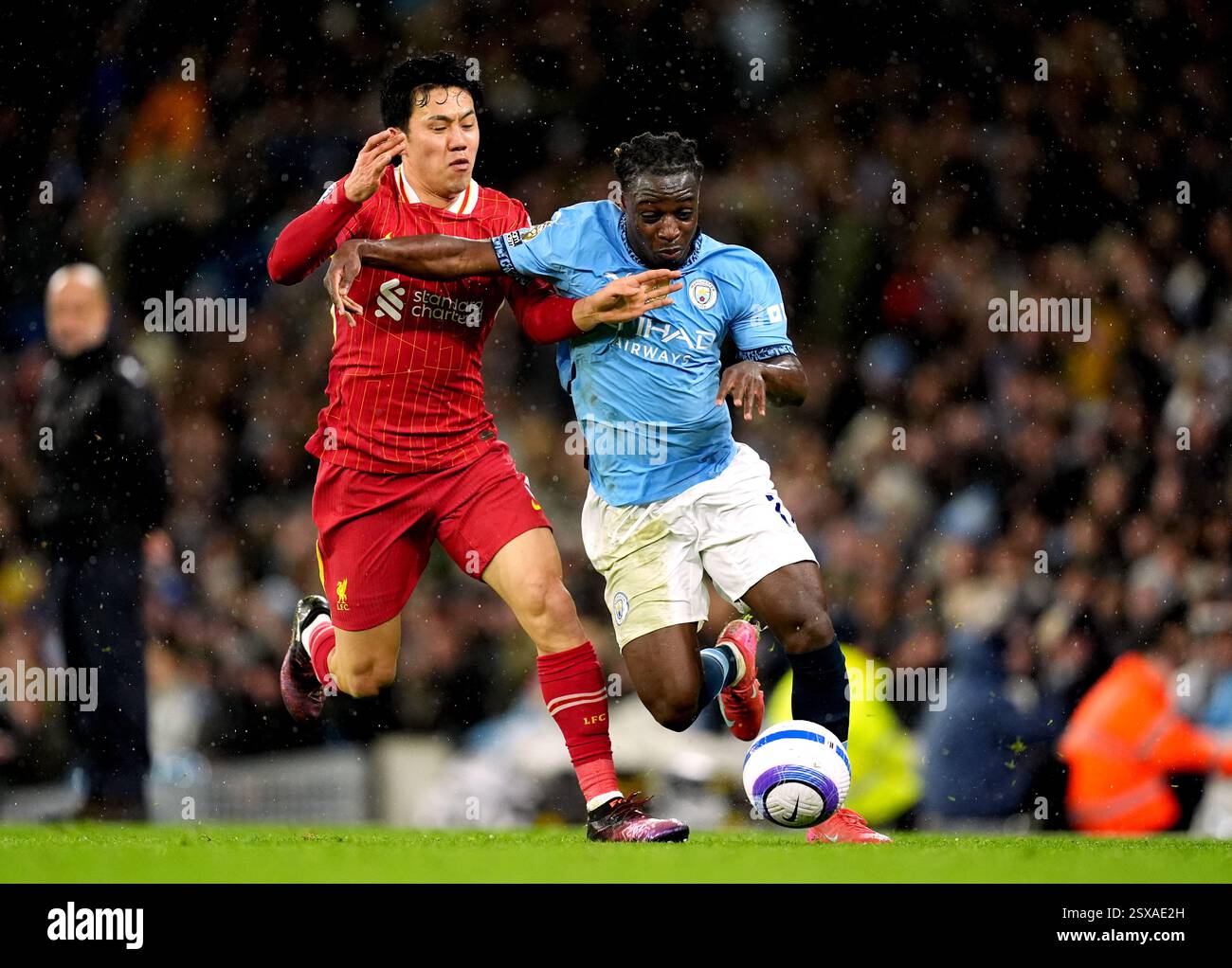 Manchester City's Jeremy Doku (right) battle for the ball with Liverpool's Wataru Endo during ...