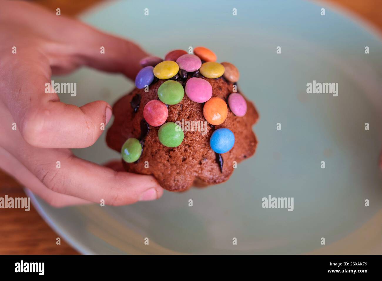 child's hand holding decorated homemade baked muffin with colorful ...