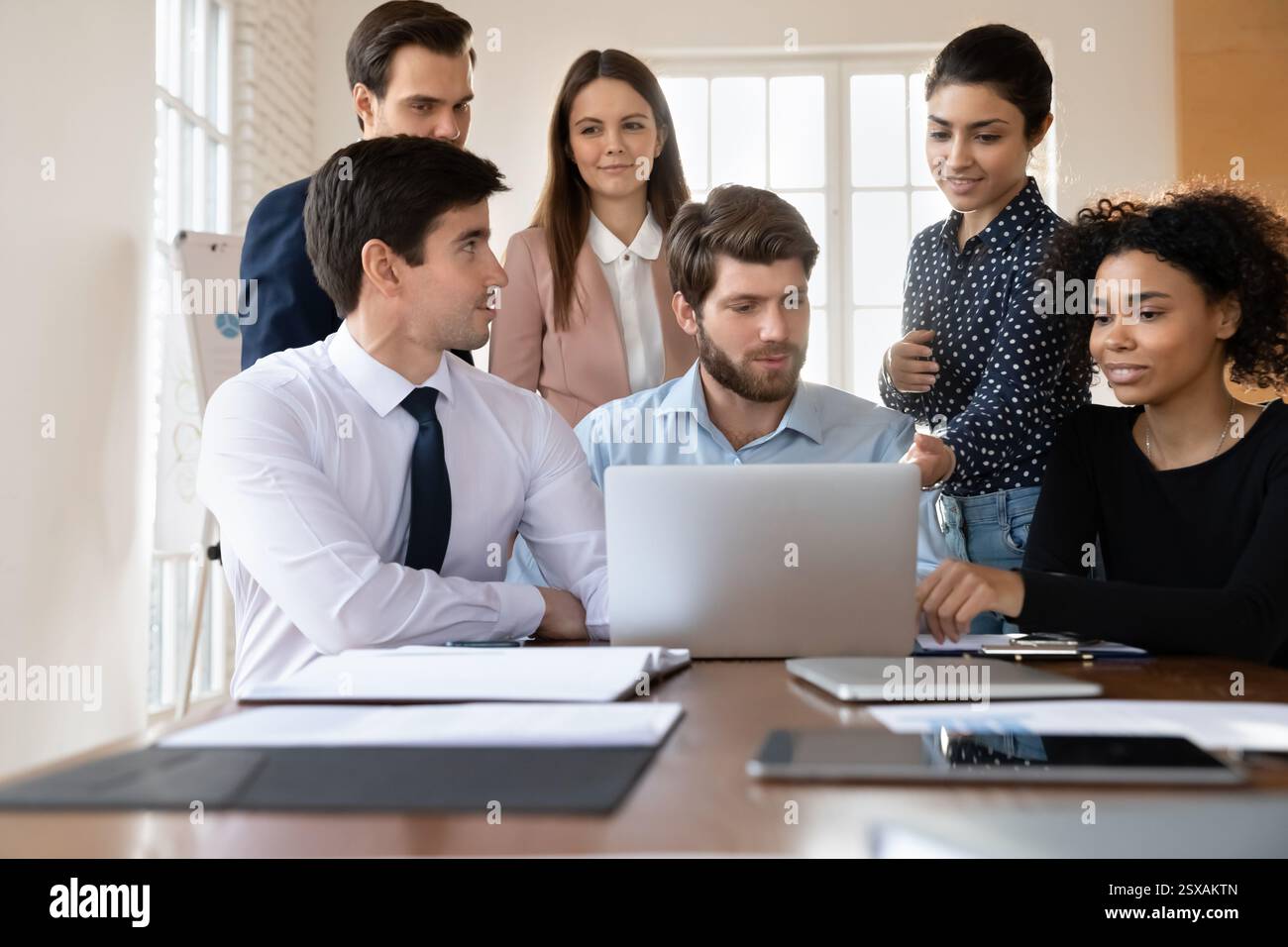 Staff using laptop working together on joint task Stock Photo - Alamy