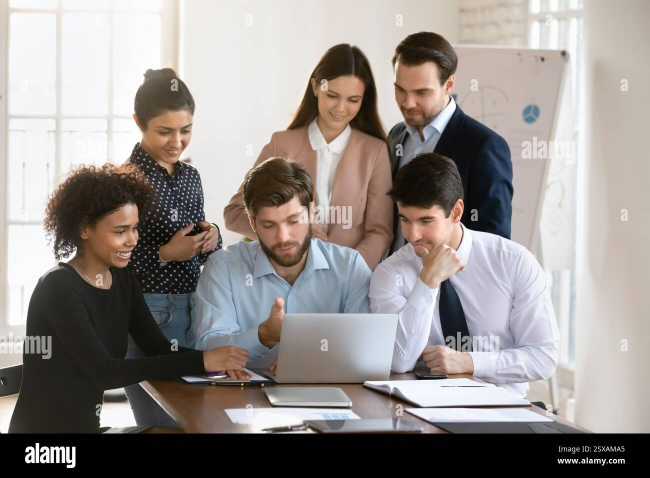 Group of people gathered around laptop engaged in discussion Stock ...