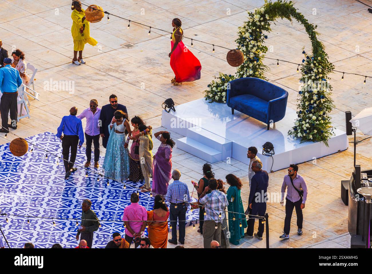 Guests in elegant attire gathering near decorated stage with floral ...
