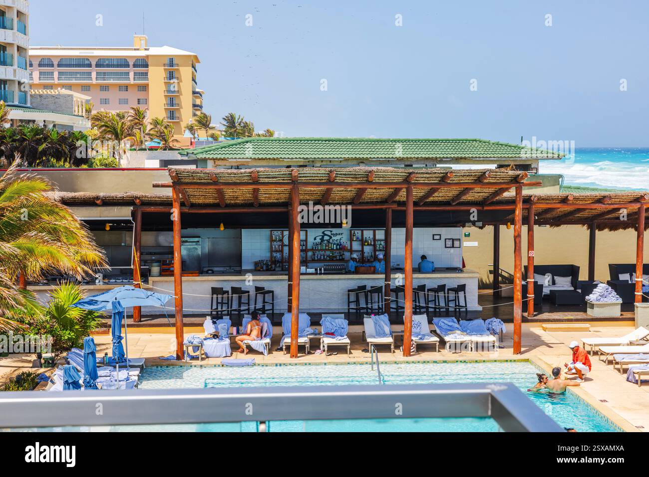 Beachfront resort with a thatched-roof pool bar, sun loungers ...