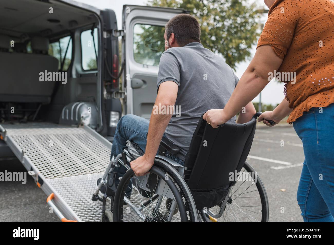 Female assistant pushing a man with disability, a wheelchair user up ...