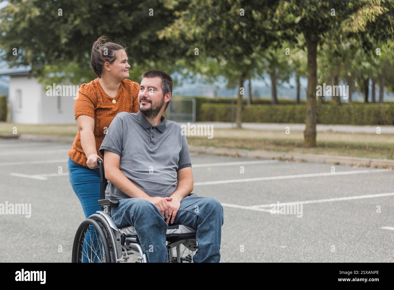 Smiling man, a wheelchair user, and his female assistant enjoying ...