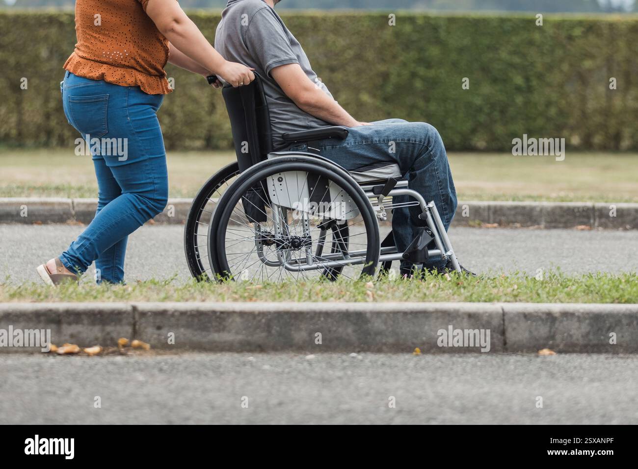 Smiling man, a wheelchair user, and his female assistant enjoying ...