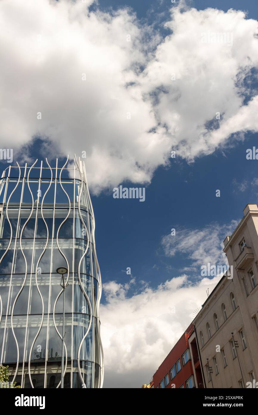 A contemporary glass building featuring a wavy metal facade against a ...