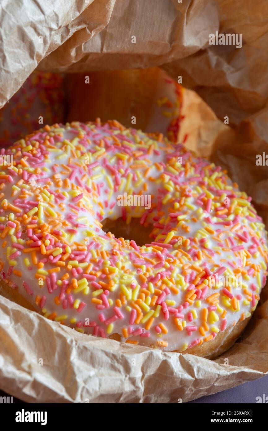 Iced ring doughnuts sprinkled with hundreds and thousands in a brown ...