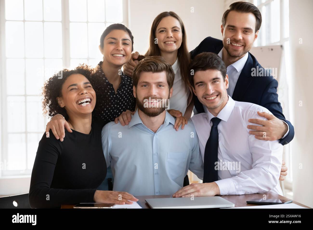 Group of young diverse colleagues hugging, celebrate shared success ...