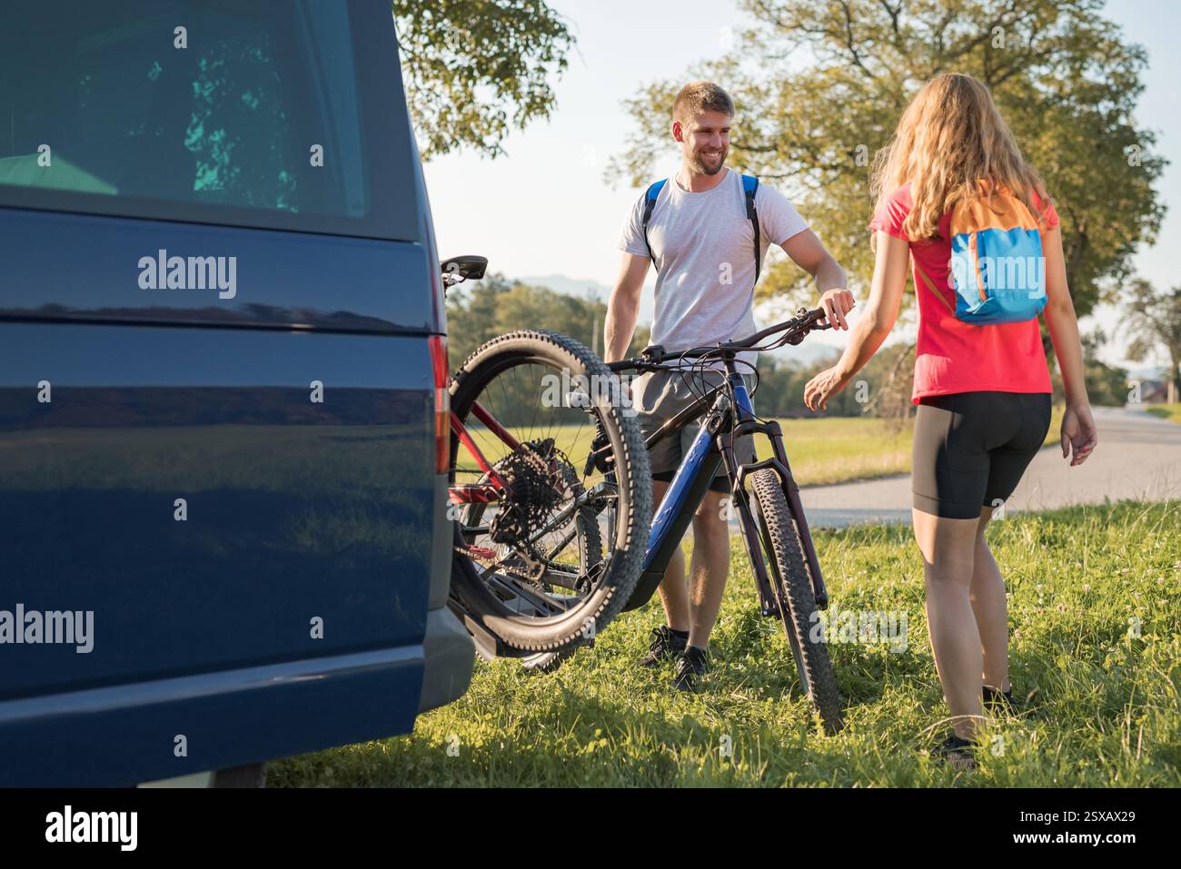 Young man and a woman preparing for off-road biking, taking down ...