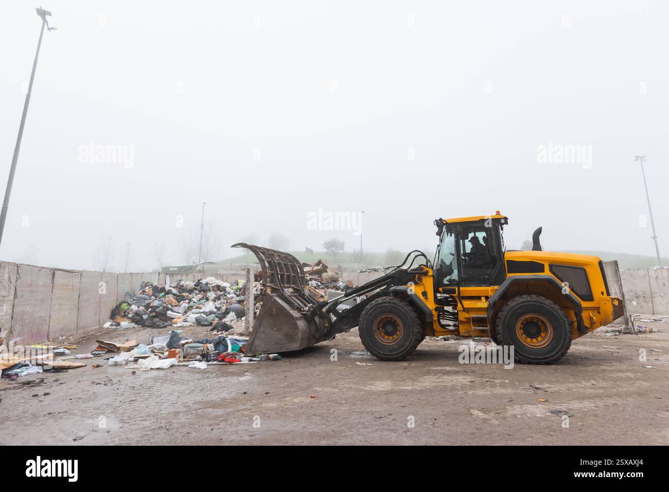 Yellow wheel loader, with lifted scrap grapple, moving along the ...