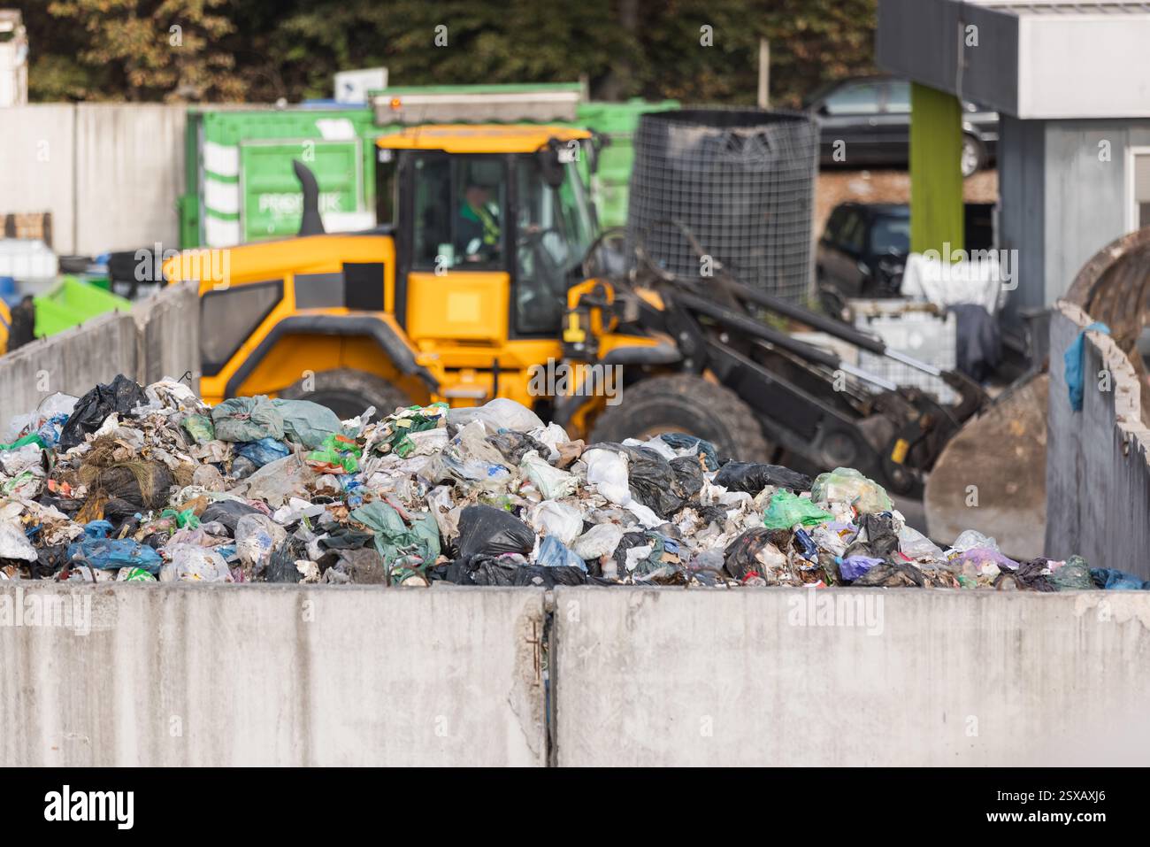 Yellow skid steer loader moving wooden waste material, shaking out a ...