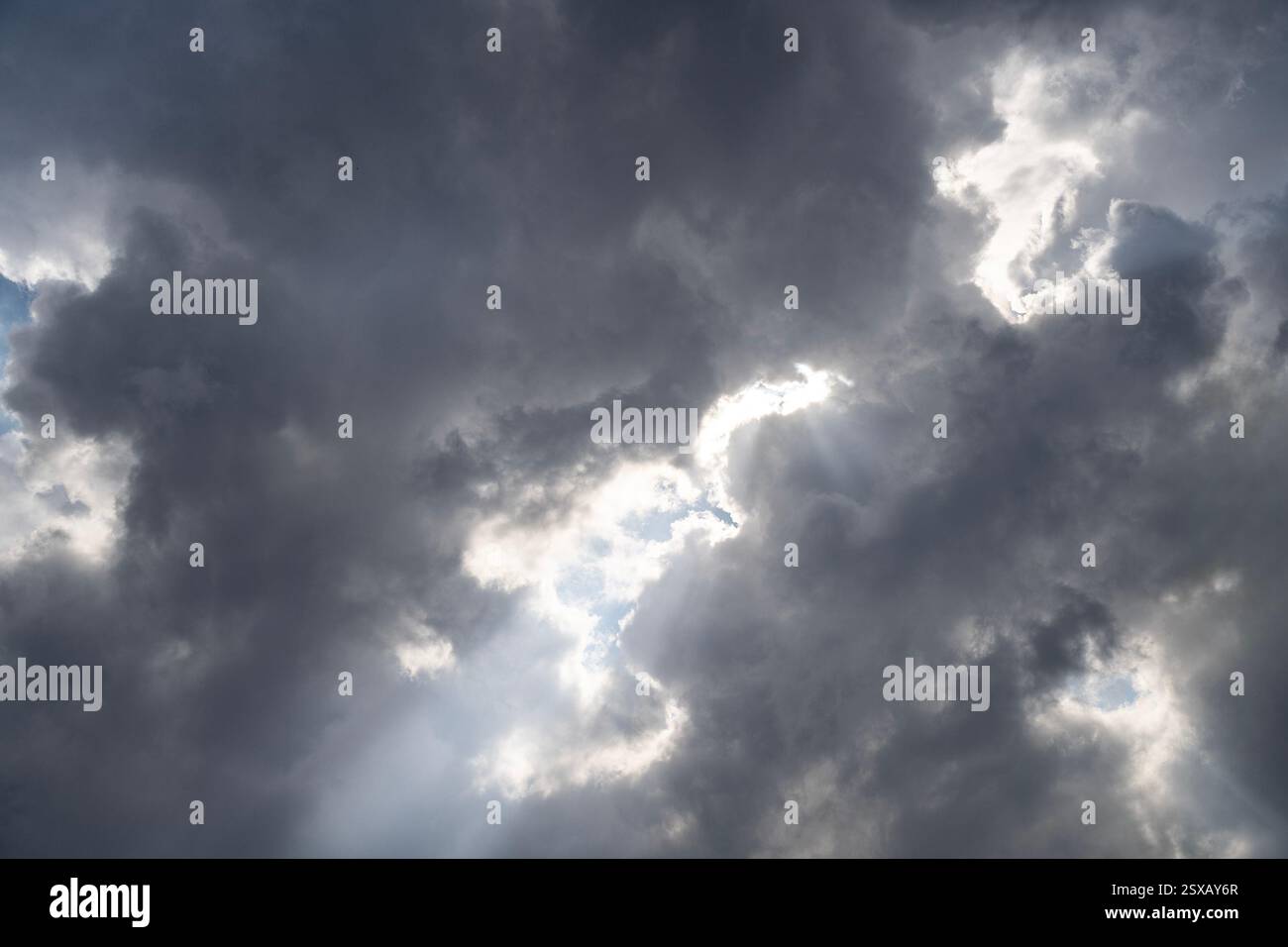 Sun rays showing through an opening in gray storm clouds Stock Photo ...