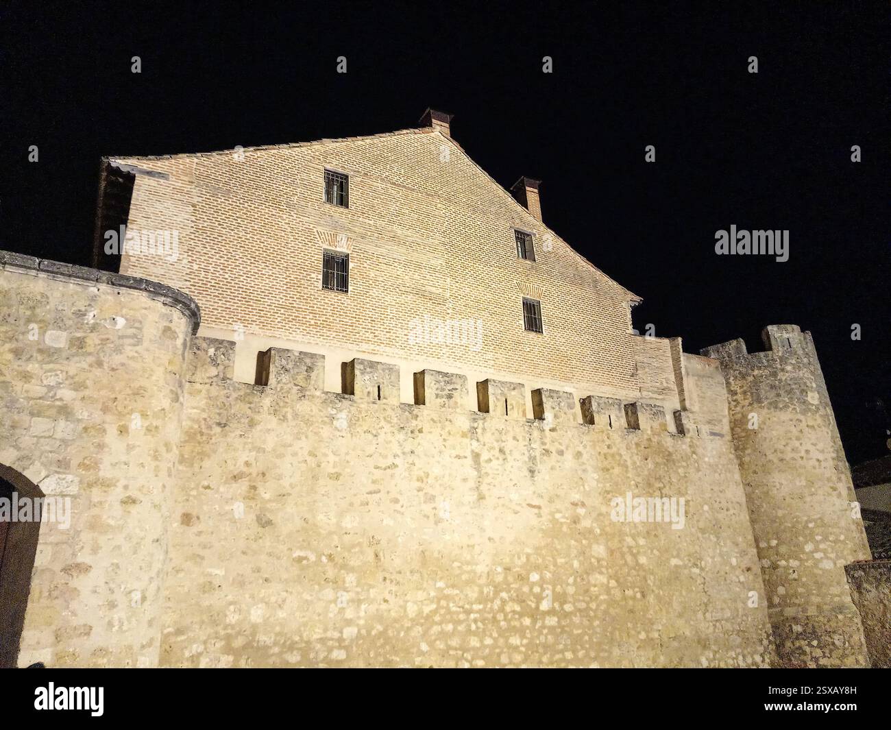 Nighttime view of a historic brick building behind the medieval stone ...