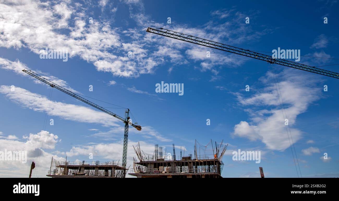 Construction site with multiple cranes against a bright blue sky with ...