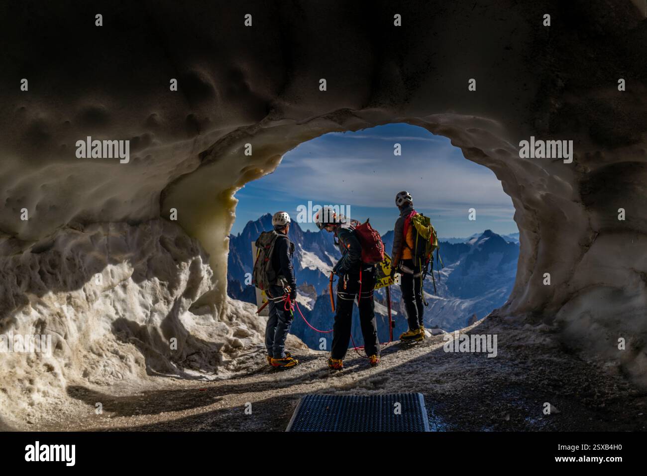 Alpinists standing at the entrance of ice cave at the Aiguille du Midi ...