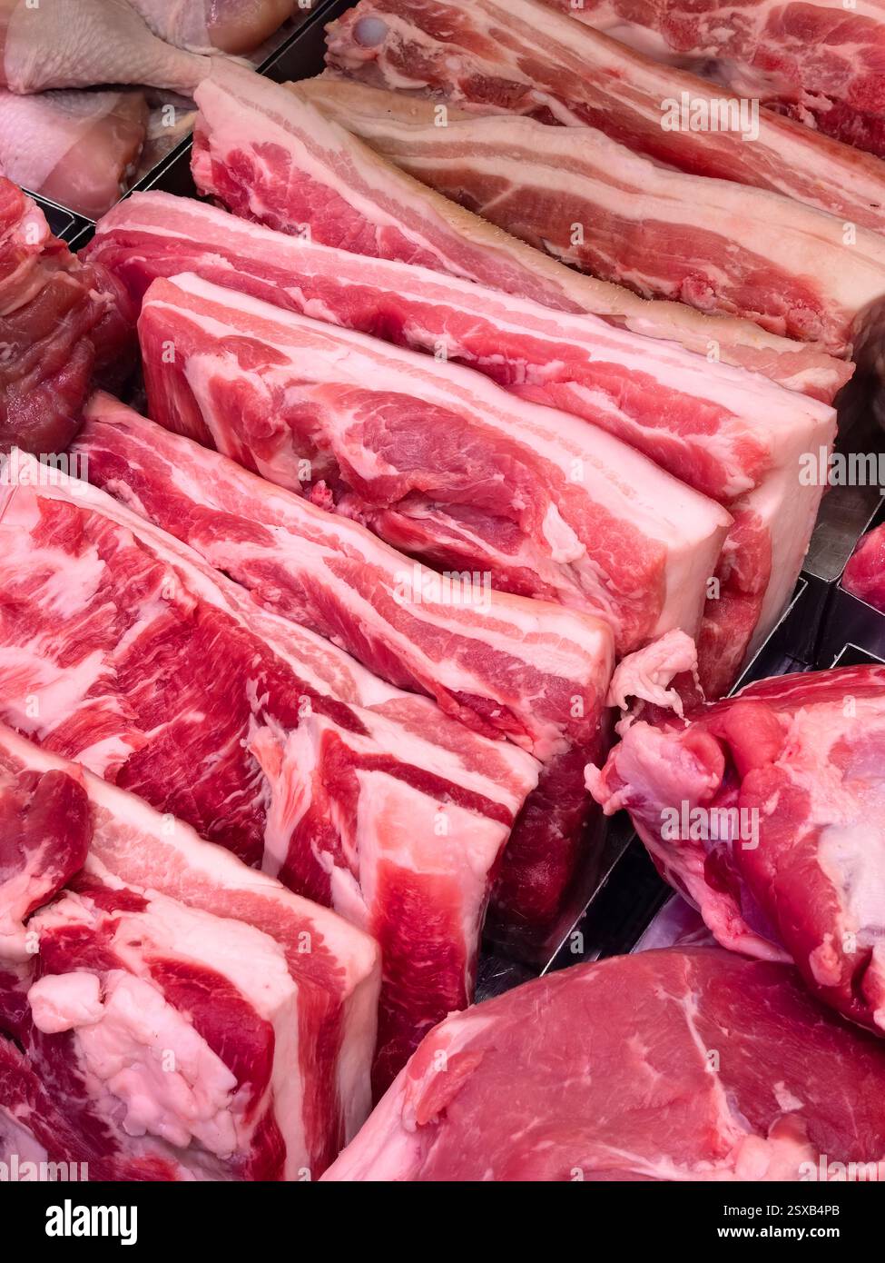 In a lively marketplace, vibrant cuts of pork display rich colors and ...