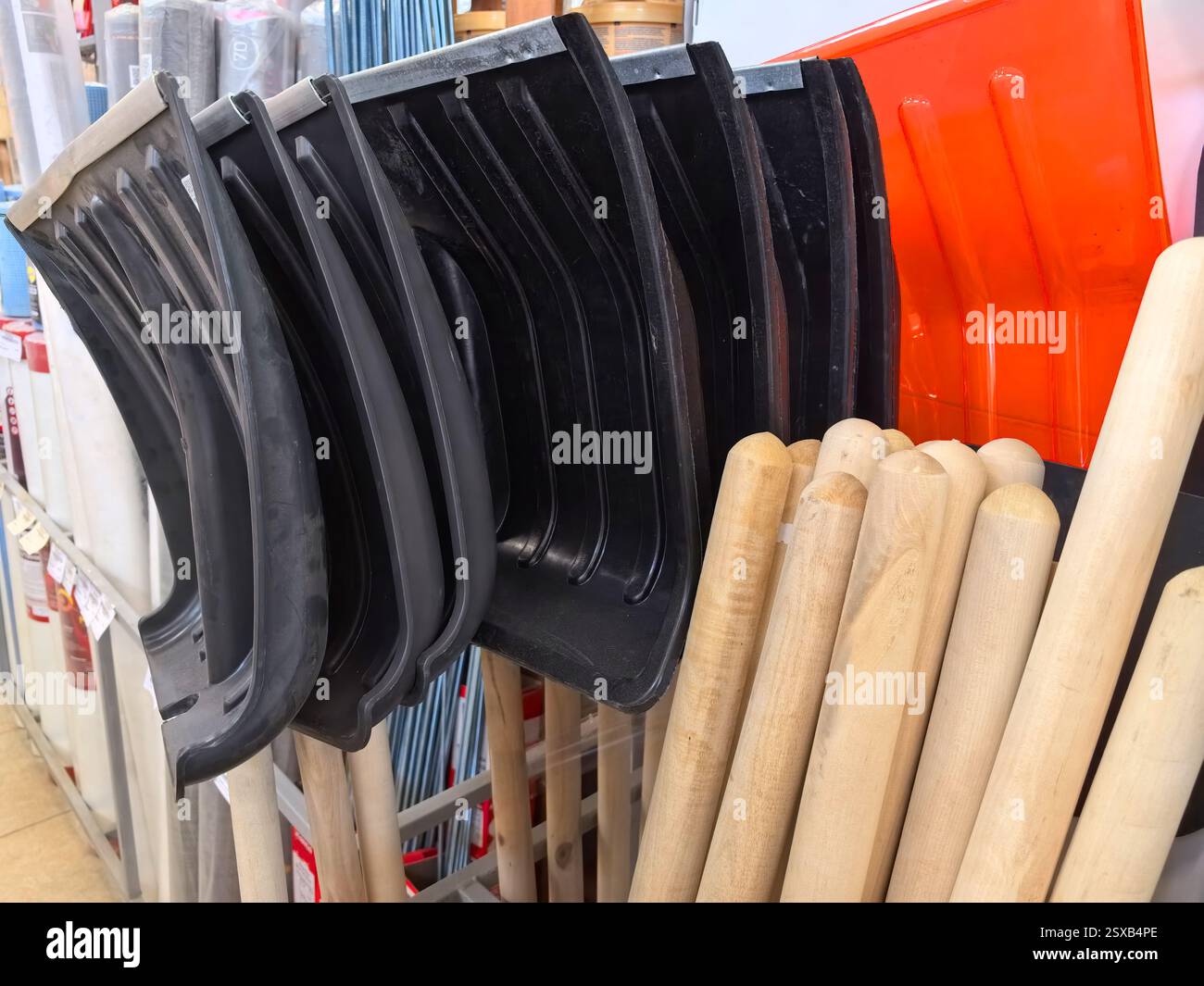 A variety of shovels and wooden handles are organized in a hardware ...