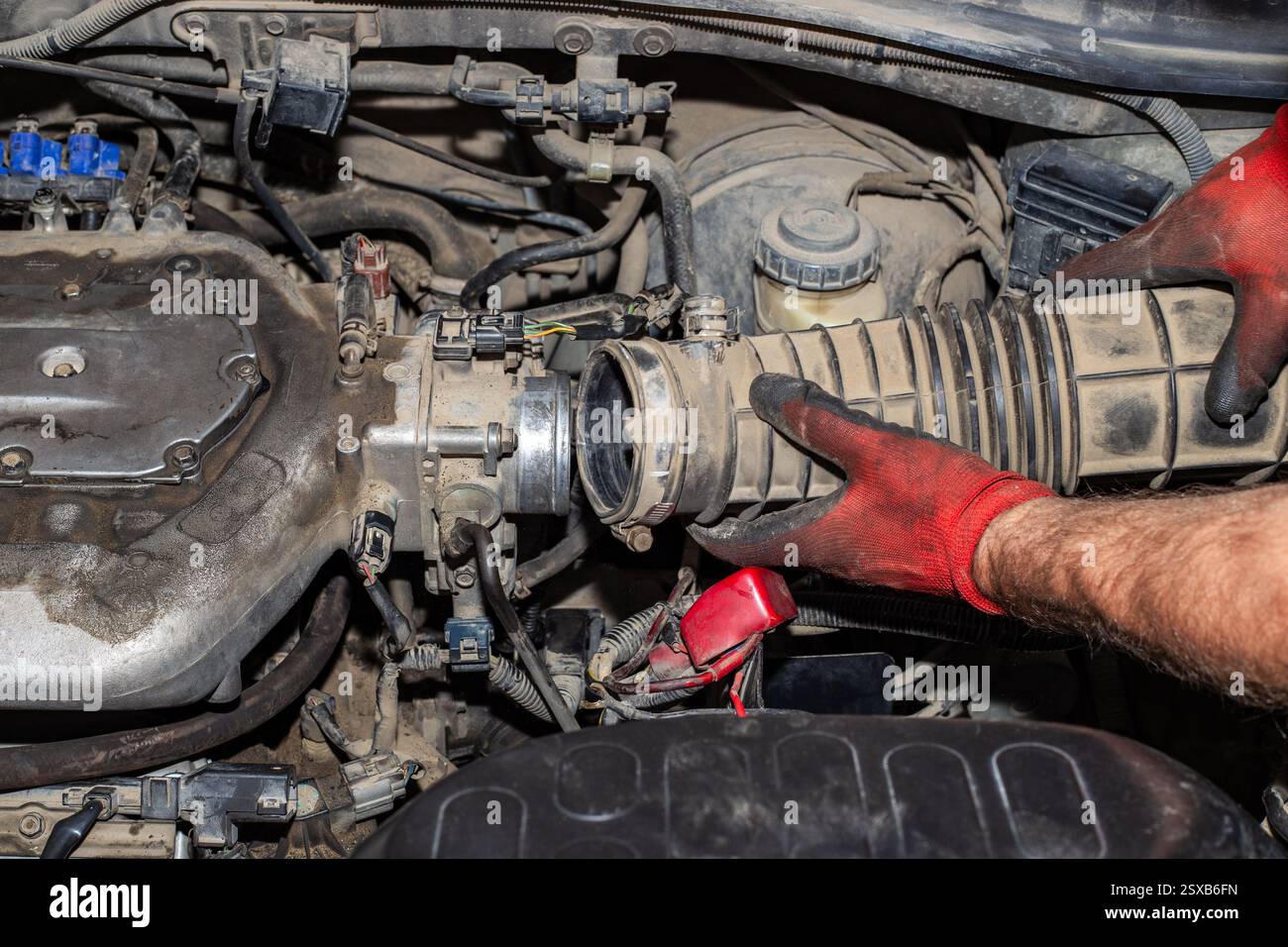 Car repair. A mechanic installs an air supply pipe onto the engine ...