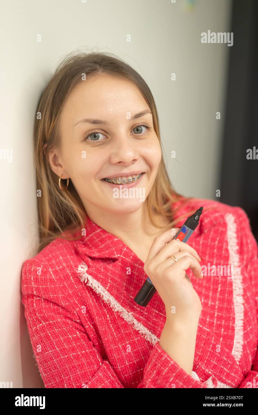 Caucasian woman with braces on teeth standing with marker at white ...