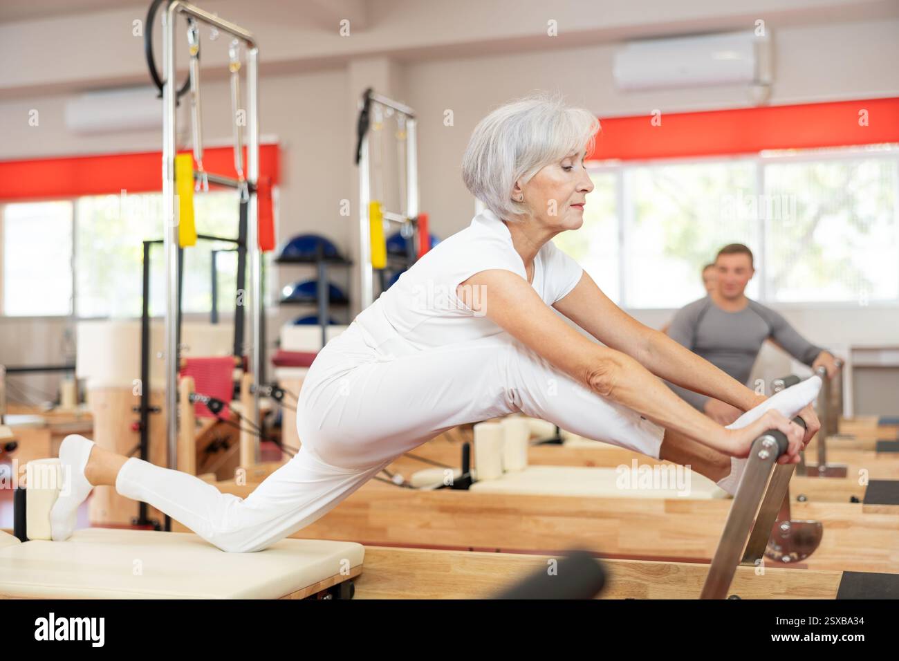 Senior woman performs exercise on reformer to improve coordination ...