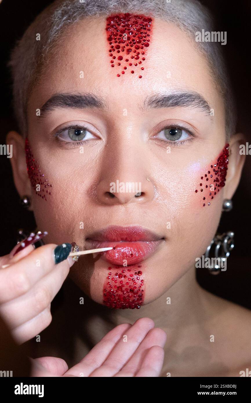 London, UK. Sunday February 23, 2025. A model has face gems applied ...