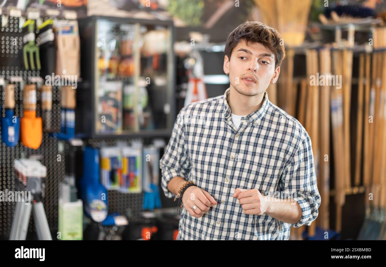 Guy choosing equipment in a garden store Stock Photo - Alamy