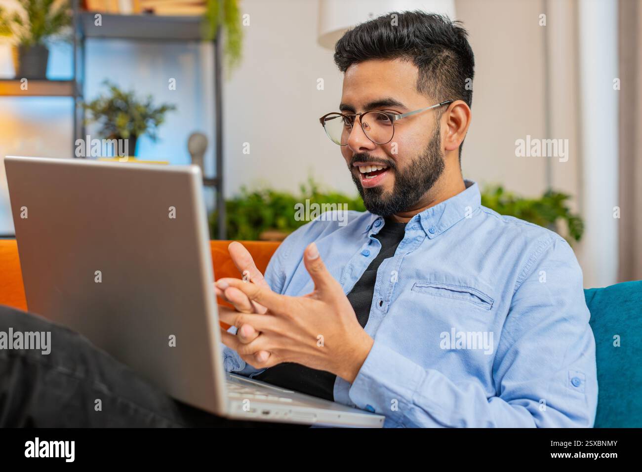 Full length of smiling Indian man typing on laptop using apps lying on ...