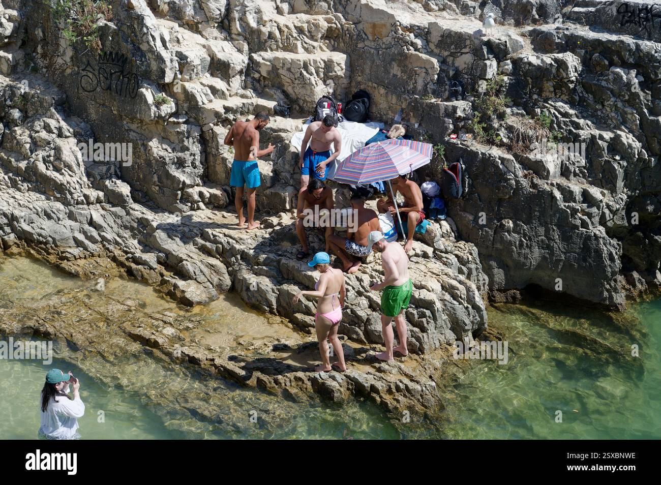 Group of friends relax on the rugged cliffs of Santa Marta beach ...