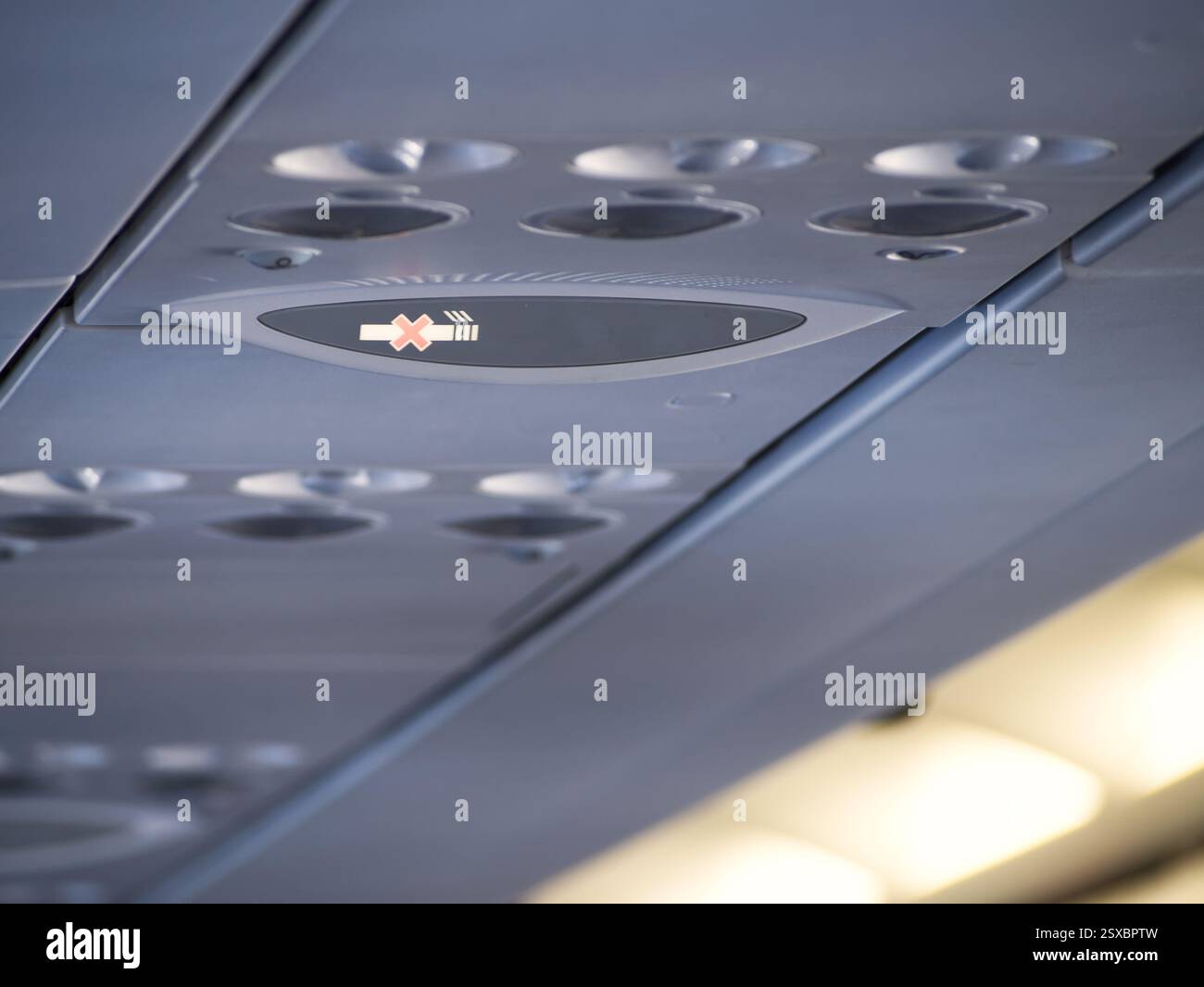 Close-up of airplane ceiling panel showing air vents and illuminated no ...