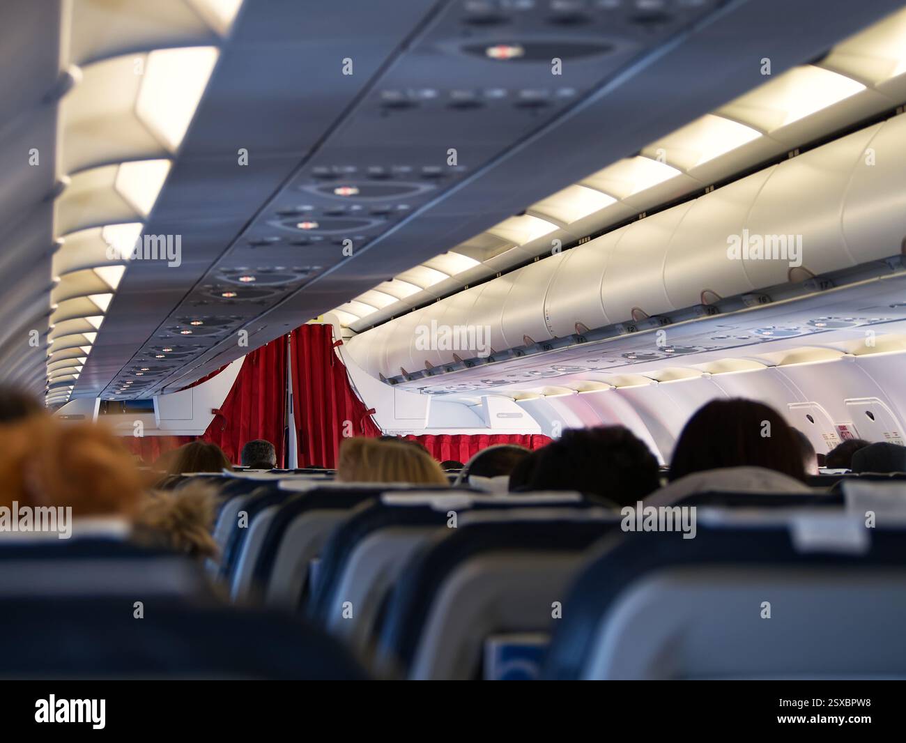 Airplane cabin with passengers, overhead compartments, and a red ...