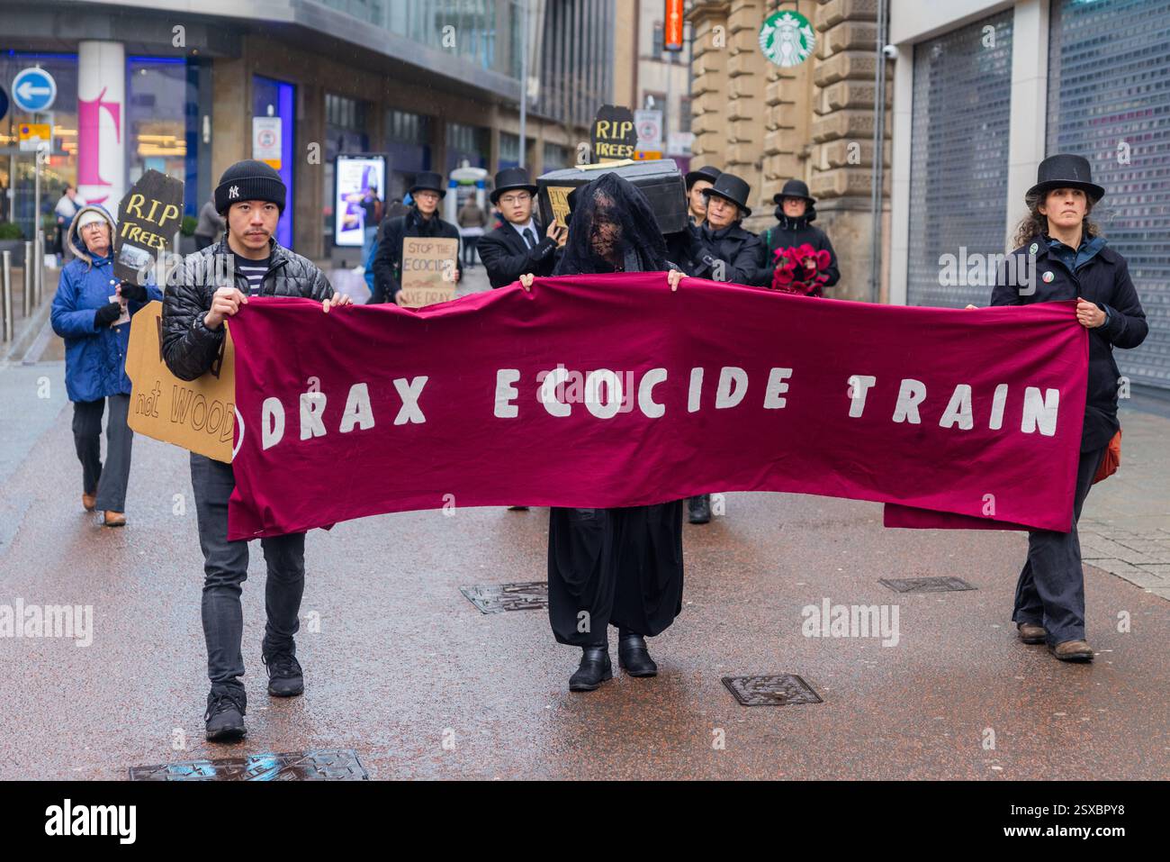 Leeds, UK. 23 FEB, 2025. Mourners hold "Drax Ecocide Train" banner as a ...