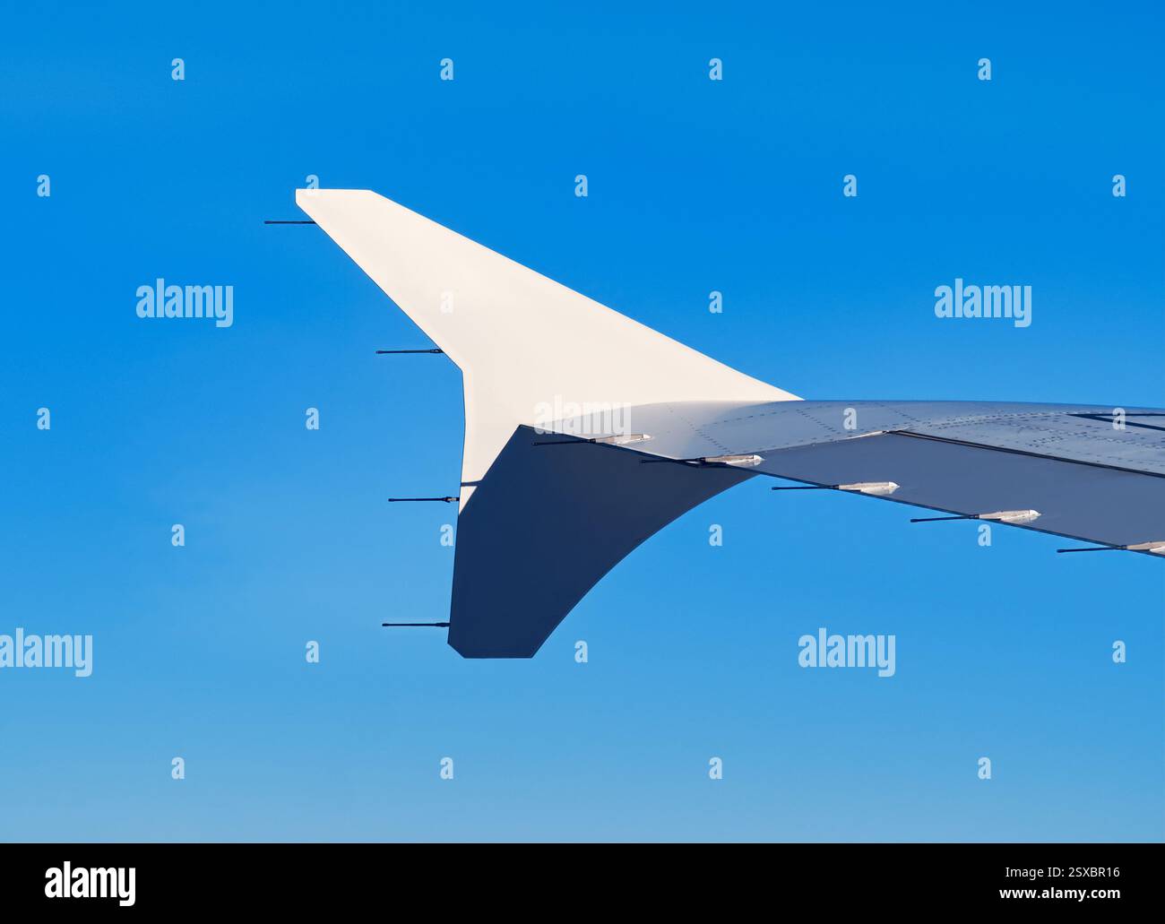 White aircraft wing tip with winglet visible against vibrant blue sky background Stock Photo - Alamy