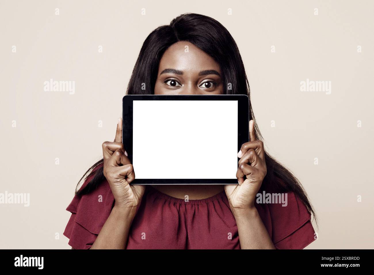 Long-haired black woman hiding behind digital tablet with empty screen ...