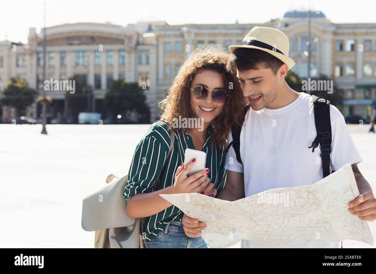 Couple of tourists checking location in smartphone and paper map Stock ...
