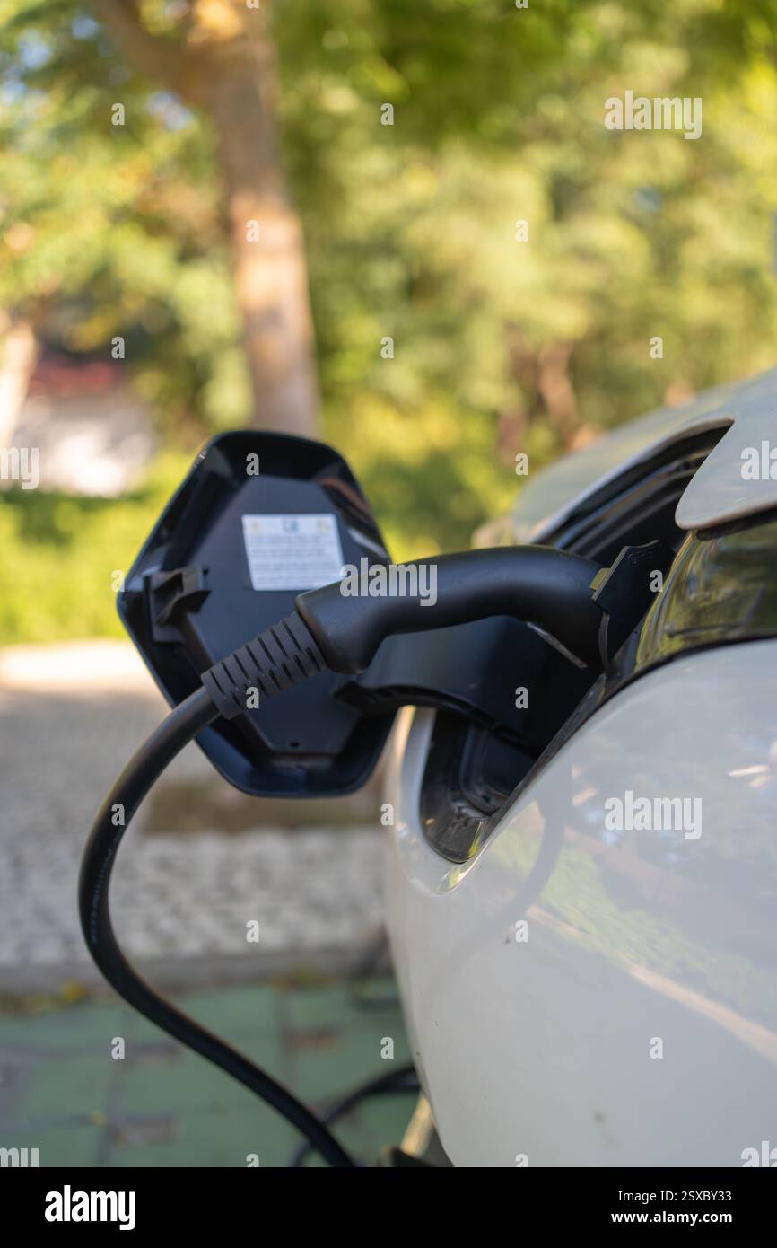 Closeup shot of an EV charger handle connected to electric car at ...