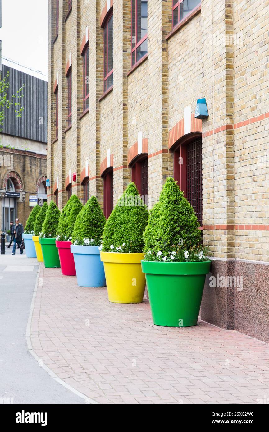 Colorful planters with topiary shrubs line the sidewalk outside a brick ...