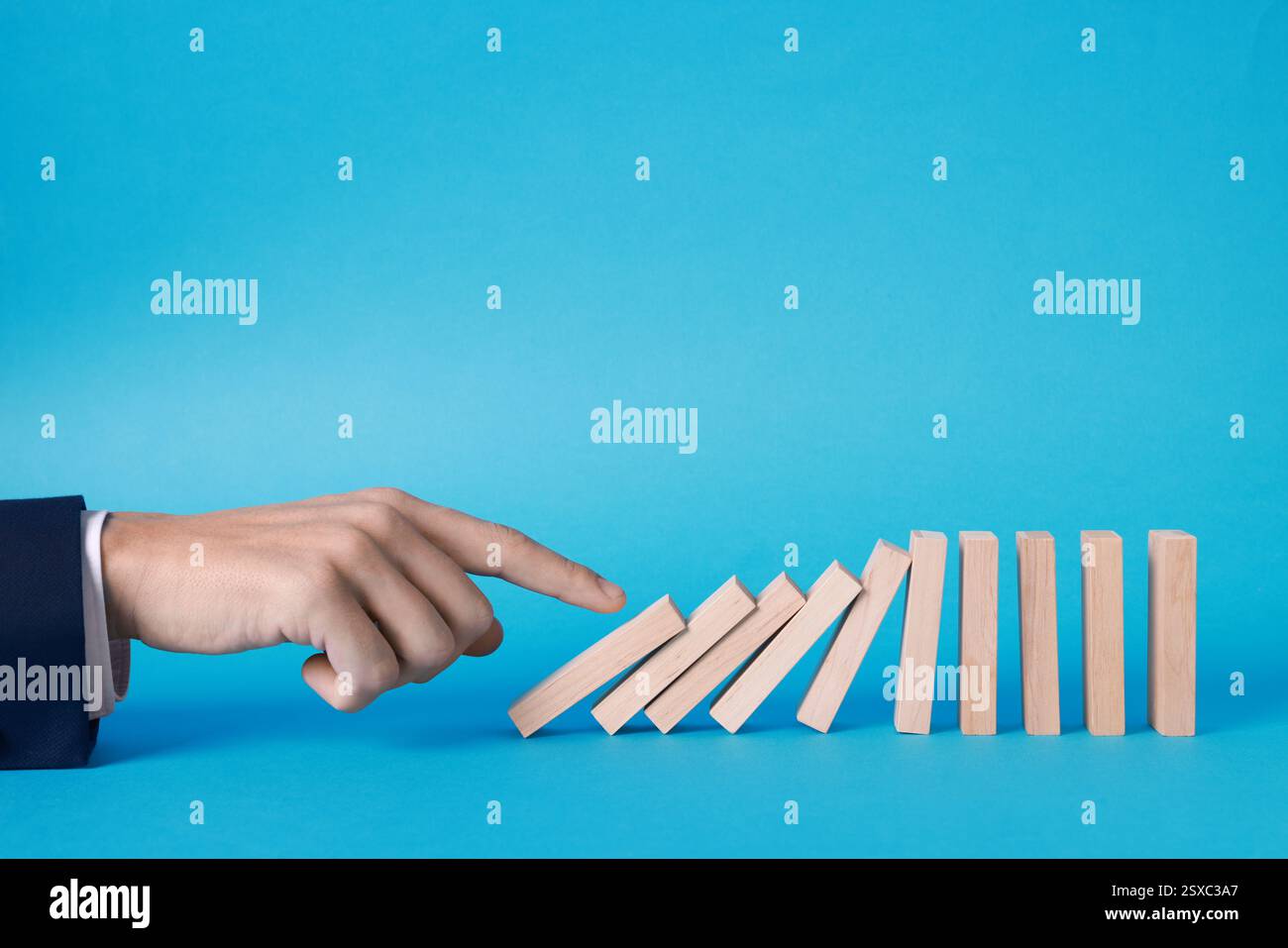 Domino effect. Man pushing wooden blocks on light blue background ...