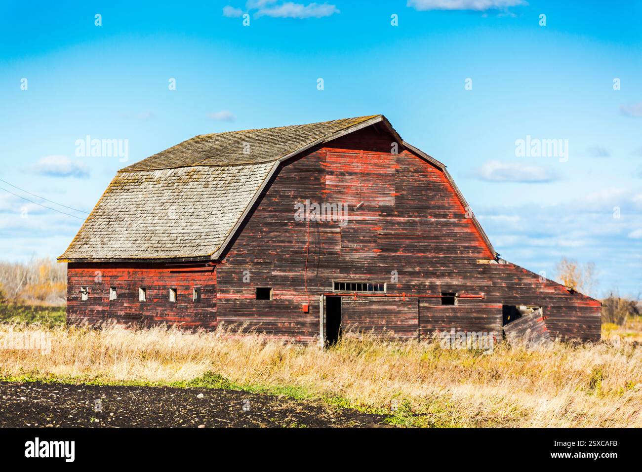 Red barn with a slanted roof. The barn is empty and has a lot of ...