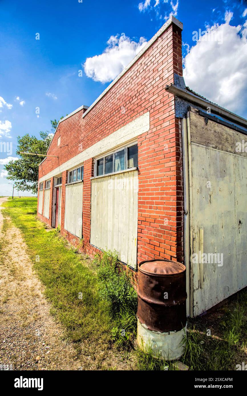 Brick building with a barrel on the ground. The barrel is black and ...