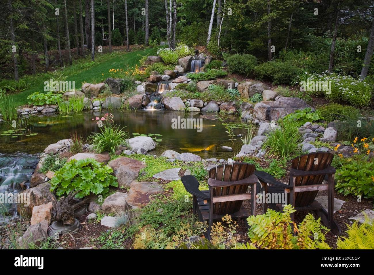 Wooden adirondack chairs next to illiuminated man-made cascading ...