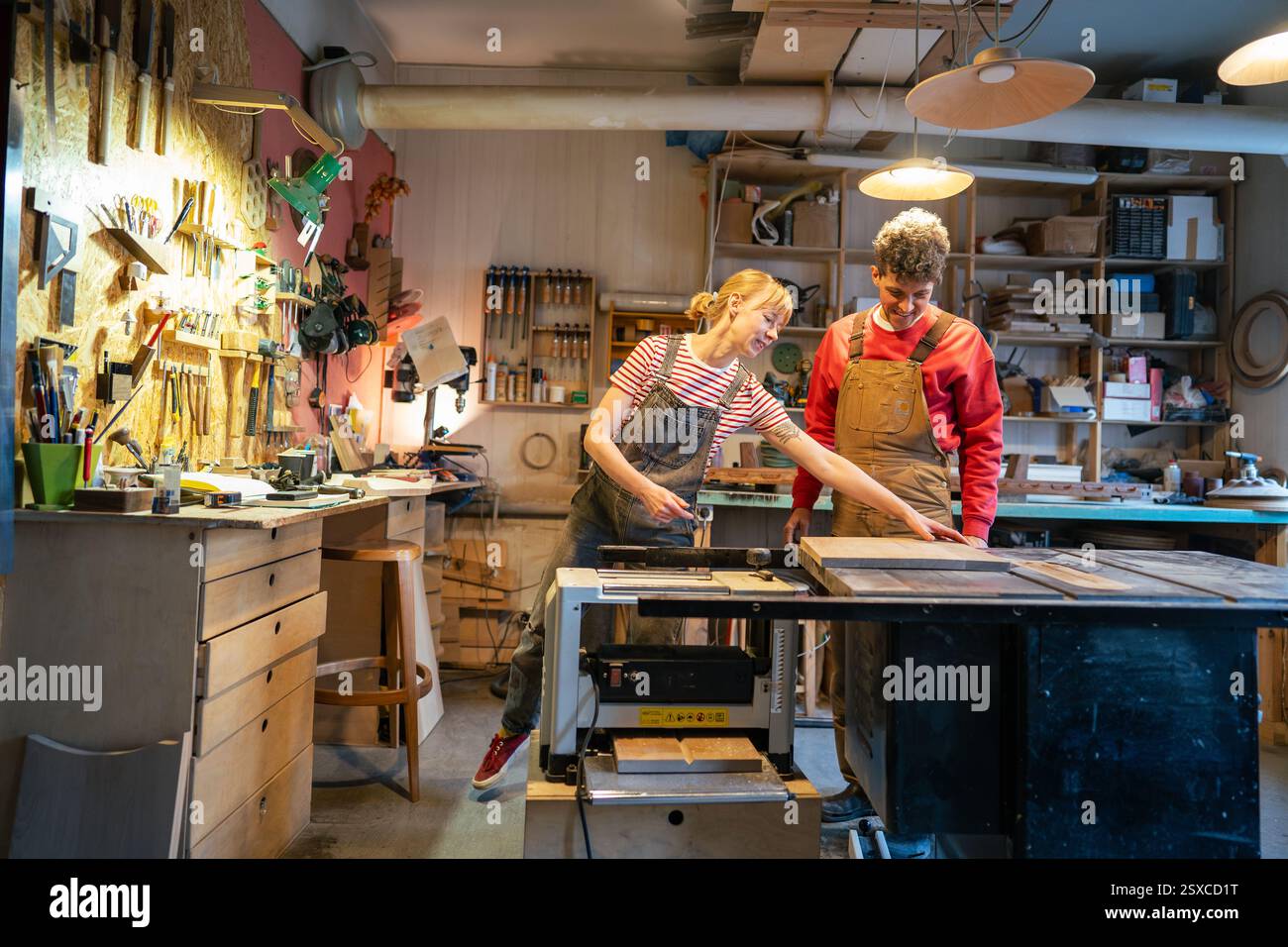 Enthusiastic couple of carpenters prepare stool base for saw machine in ...