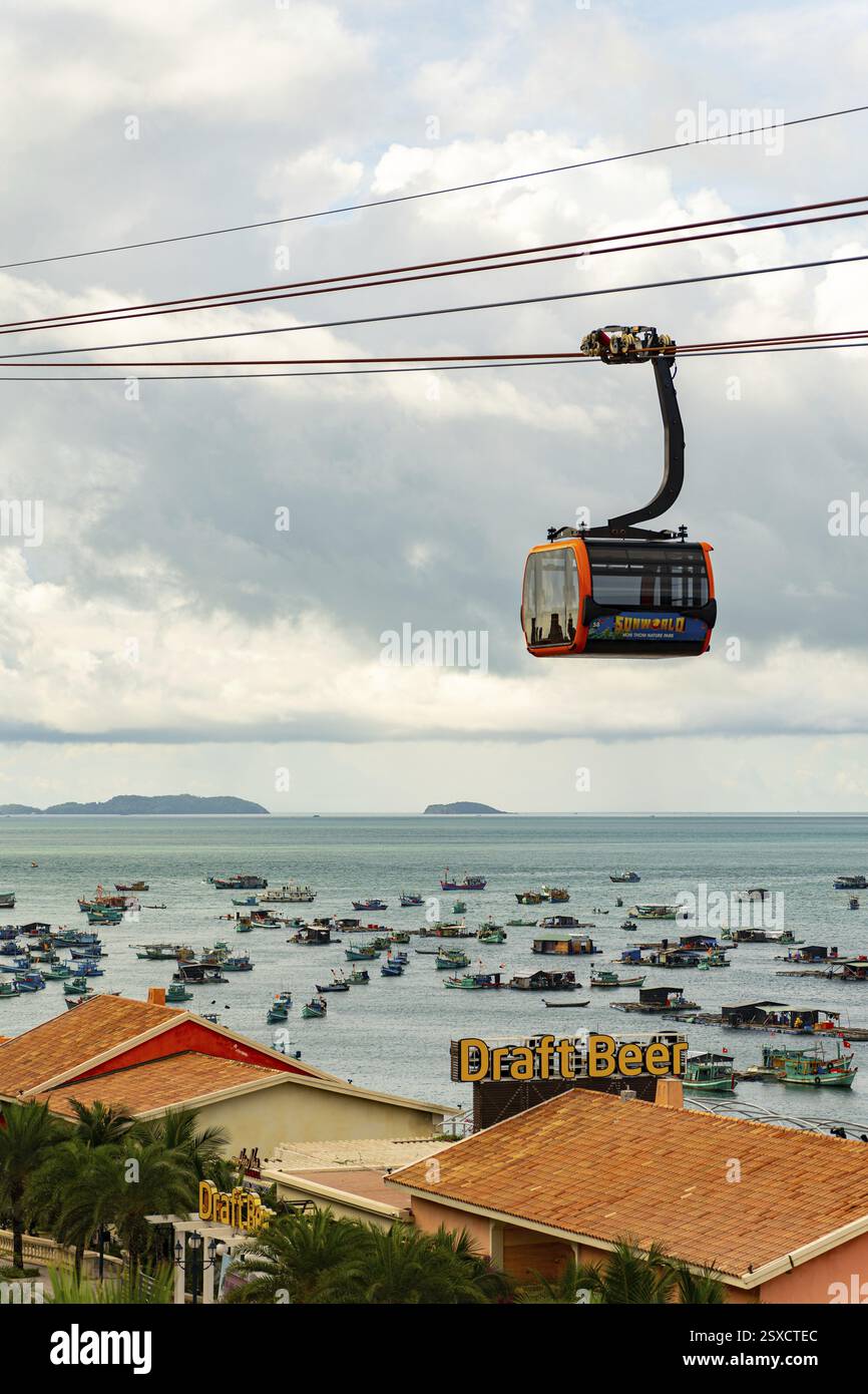 Cable car rides over the sea with distant islands and palm trees below ...