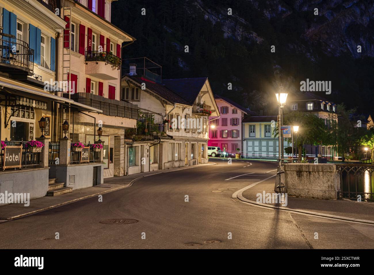 Quiet street scene with colorful buildings and street lamps at night ...